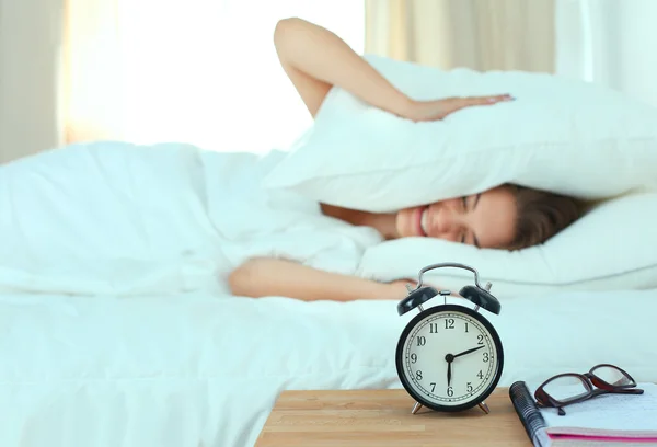 A young woman putting her alarm clock off in the morning - Stock Image ...