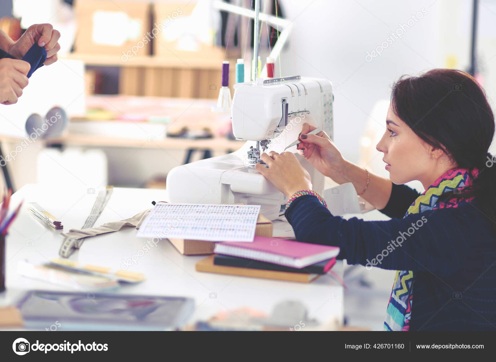 Young woman sewing while sitting at her working place Stock Photo by ...