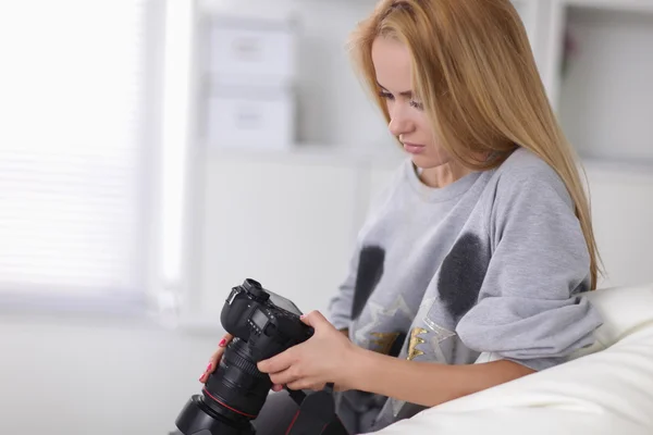 Woman sitting on a sofa in her house with camera - Stock Image - Everypixel