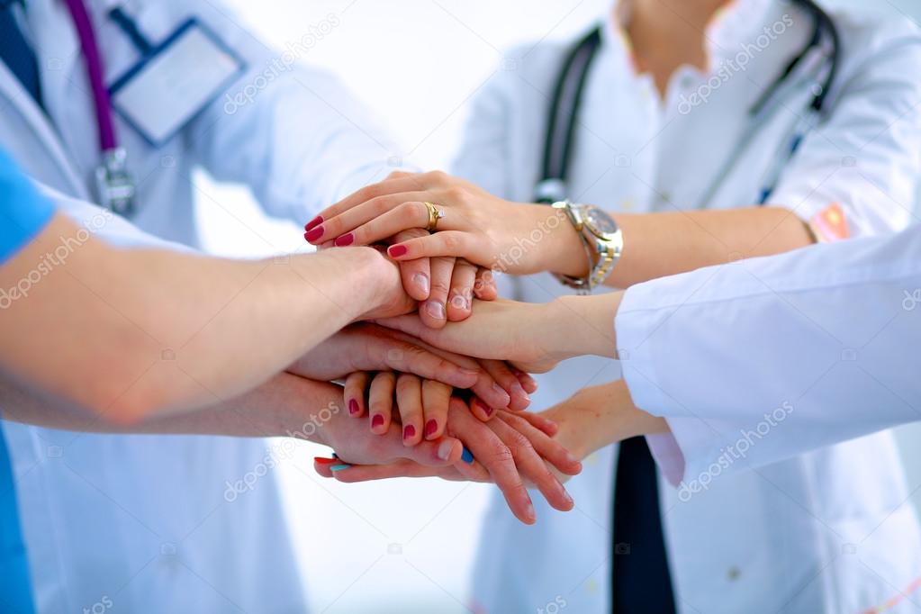 Médicos y enfermeras en un equipo médico apilándose las manos ...