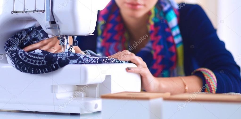 Young woman sewing while sitting at her working place Stock Photo by ...