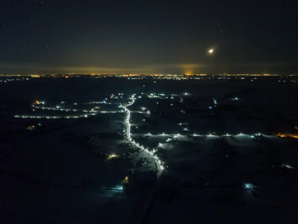 Distant lights of the night city under the starry sky. Aerial drone ...