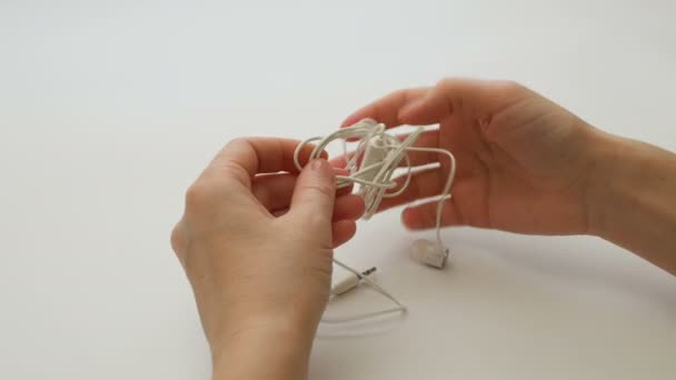 Woman untangles tangled earbuds or earphone knot — Stock Video © kirill ...