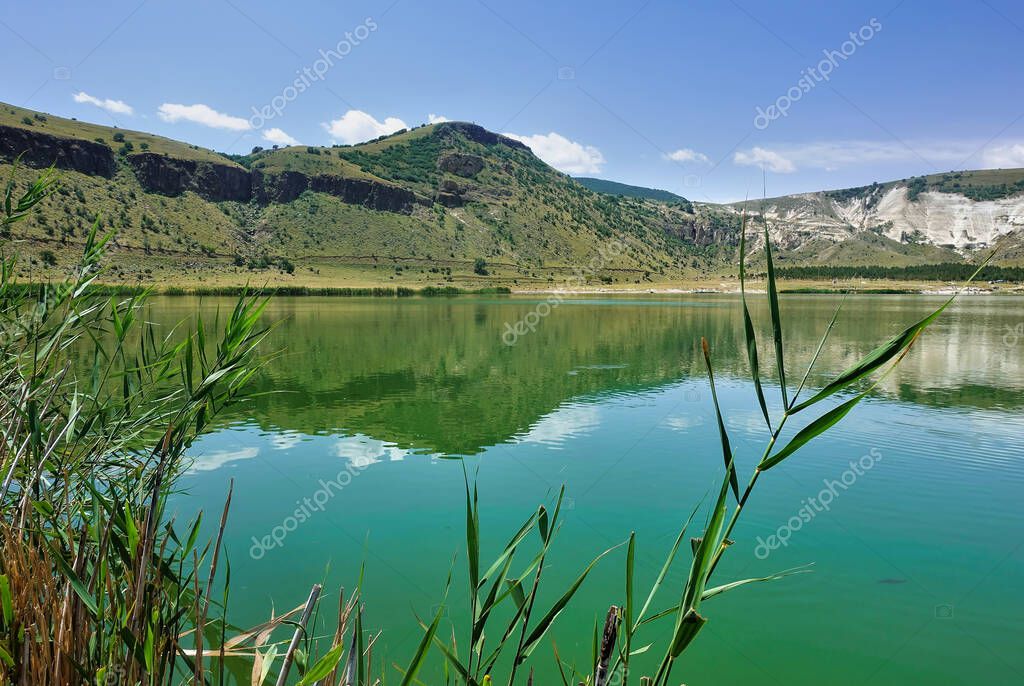 El lago volcánico Nar está rodeado de laderas montañosas. Reflejo ...