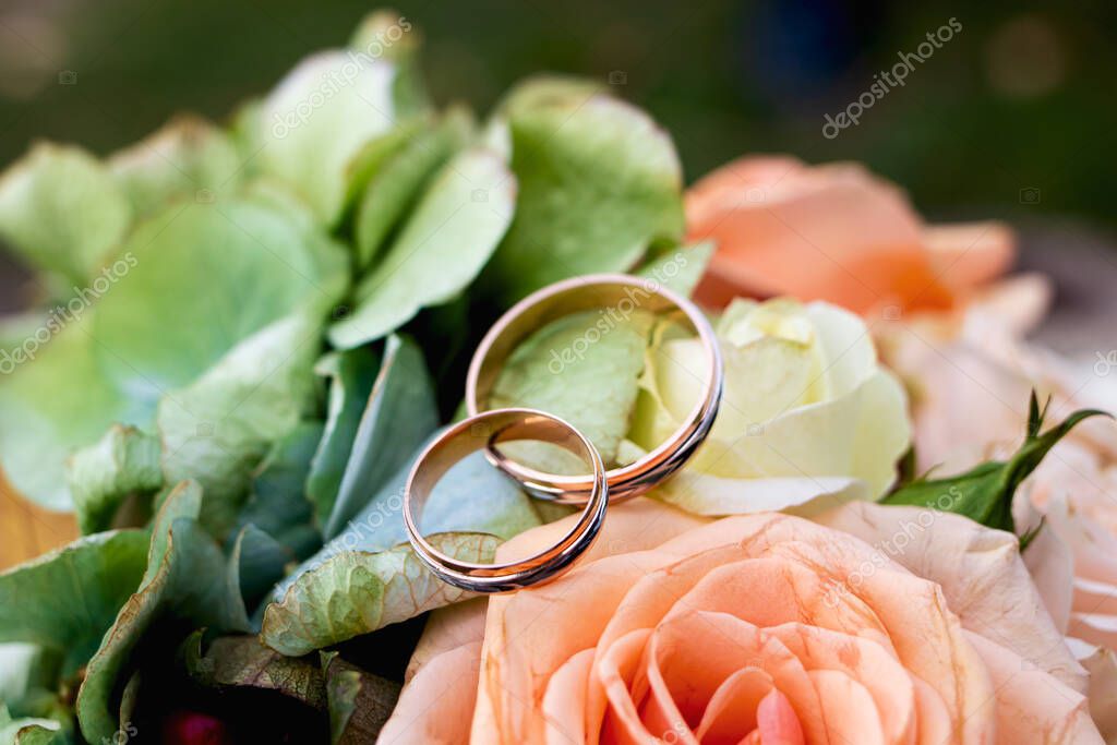 Los anillos de la novia y el novio en una hermosa flor rosa claro en el ...
