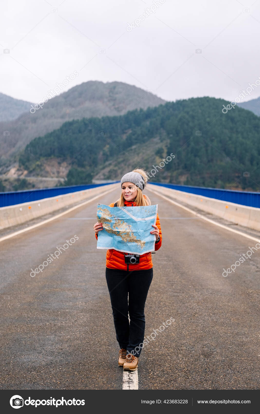 A woman with a map on a road with mountains in the background – Stock ...