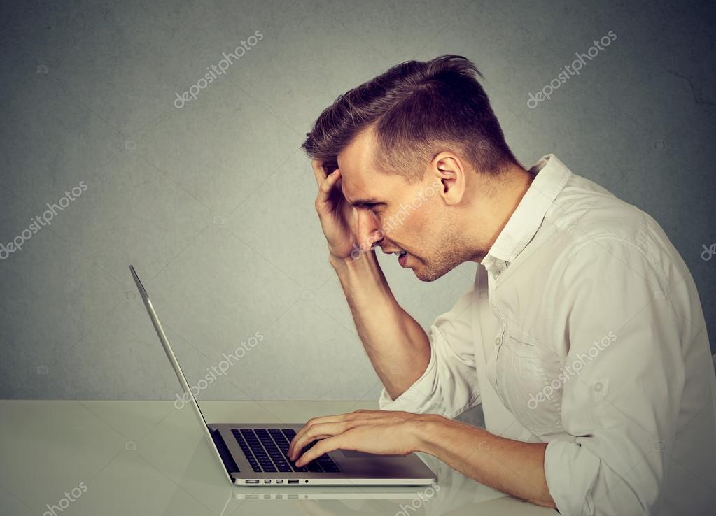 Side profile stressed man working on laptop sitting at table — Stock ...