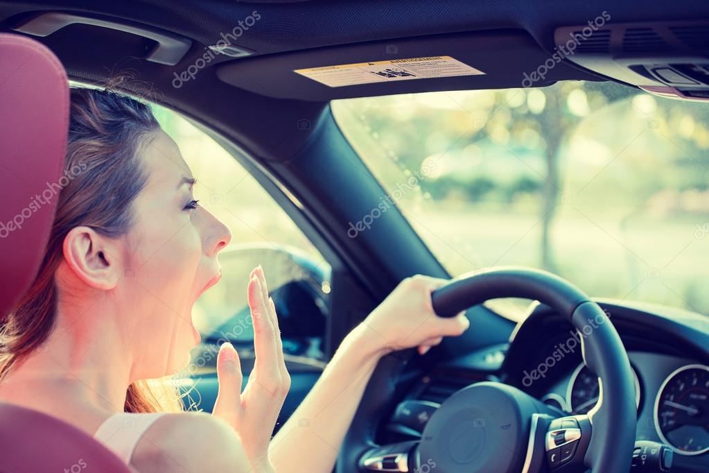 Tired, fatigued, exhausted young attractive woman driving her car ...