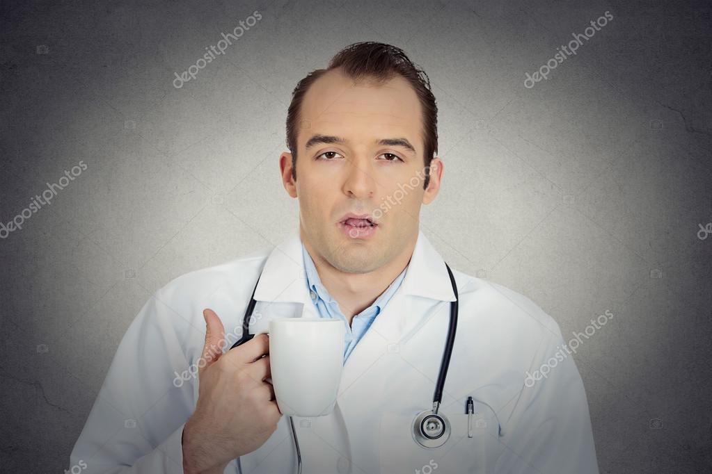 Exhausted young funny doctor holding cup coffee falling asleep Stock ...