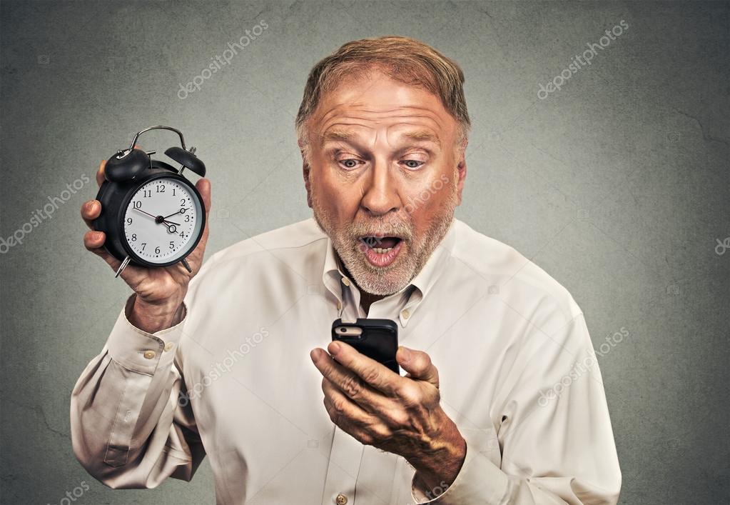Surprised business man with alarm clock looking at smart phone — Stock ...
