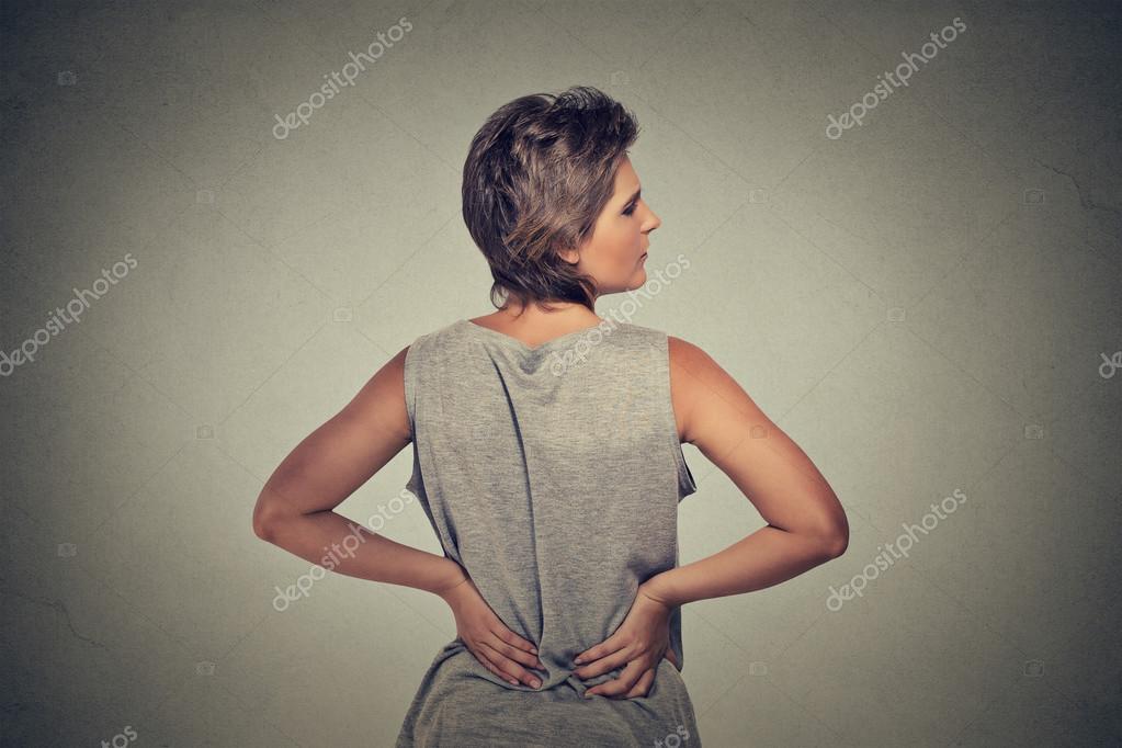 Young woman standing with backache back pain Stock Photo by ...