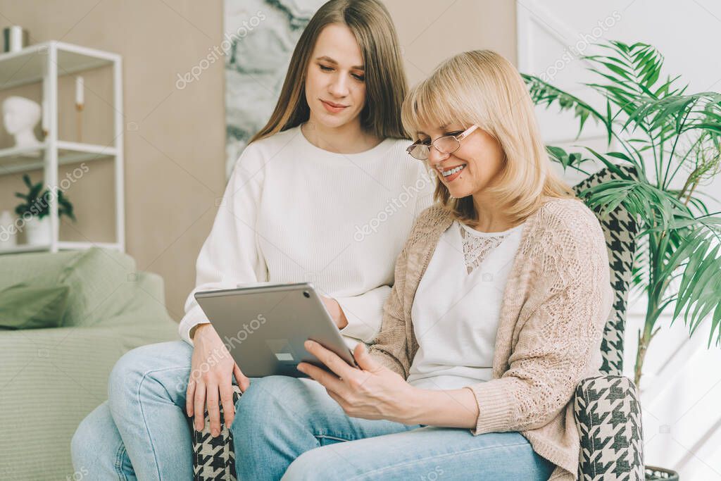 Madre e hija adulta usando tableta digital 2024