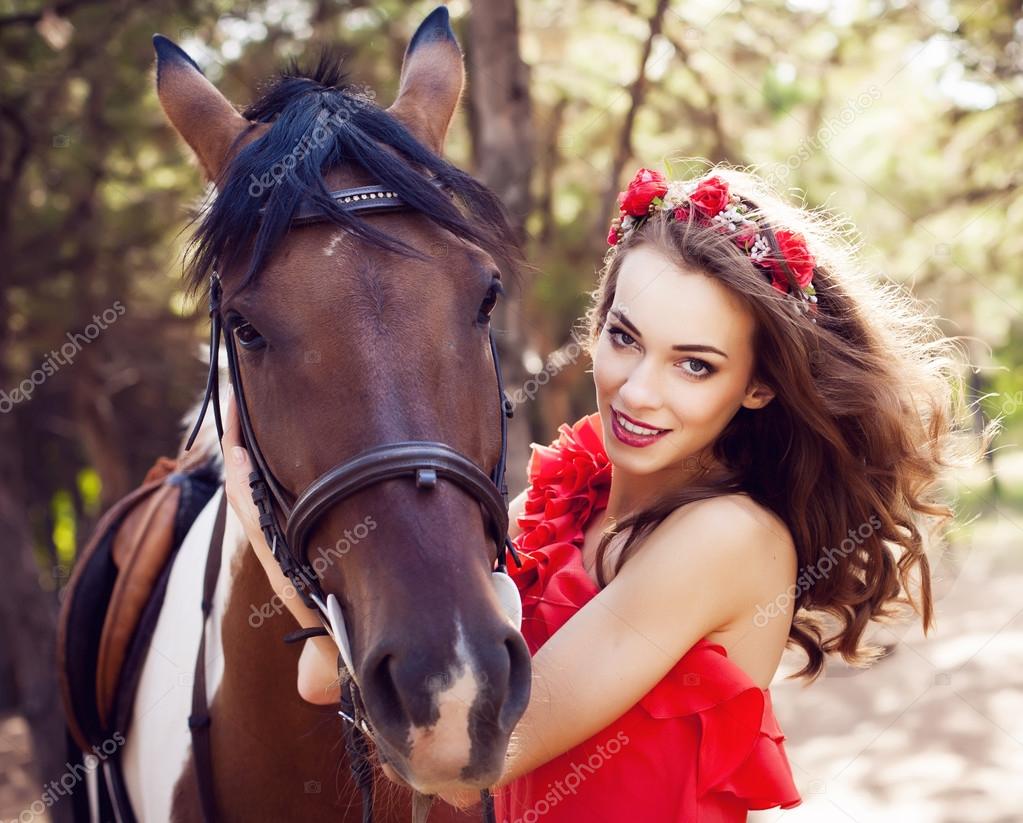 Beautiful young lady wearing red dress riding a horse at sunny summer ...