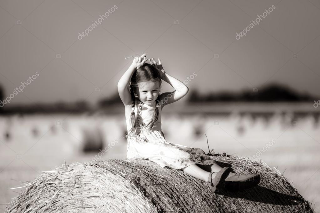 Funny cute little girl posing on the haystack in summer field — Stock ...