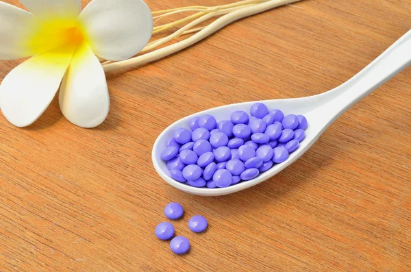 Close up many purple medicine tablet on the spoon with white flower and ...