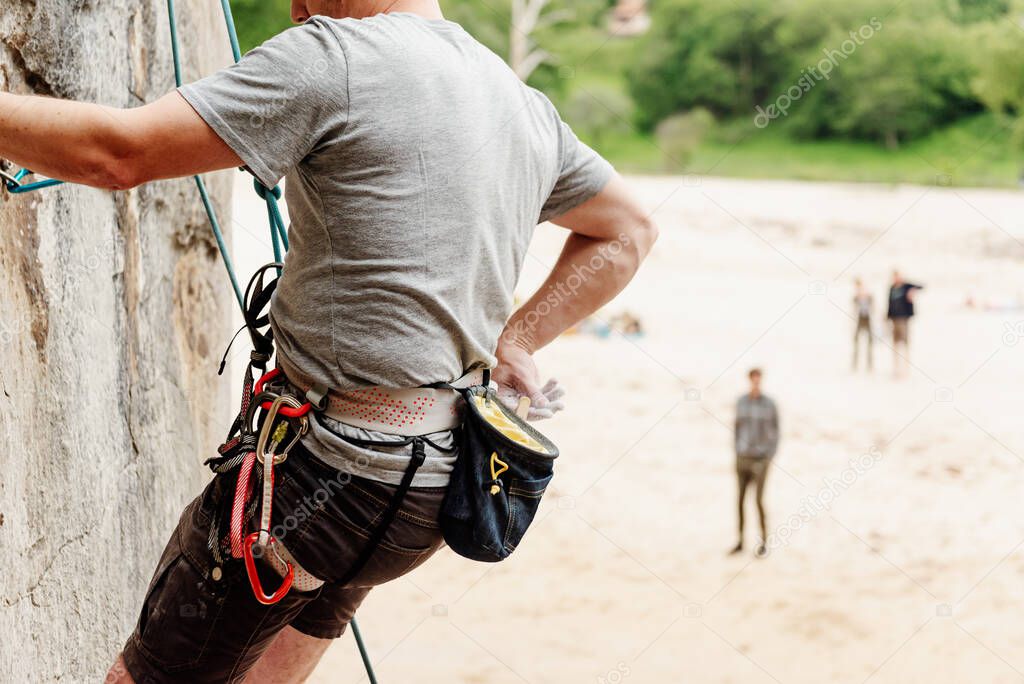 hombre irreconocible tomando magnesio de su bolso mientras hace una exposición de escalada ...