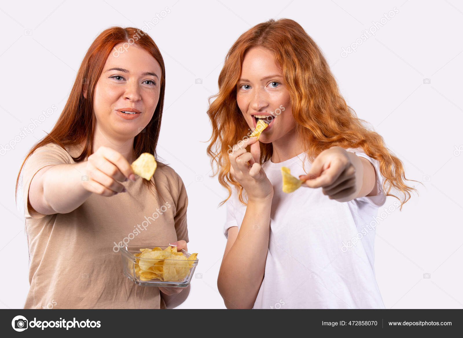 Close up of two ginger, red-haired female girls, friends holding bowl ...