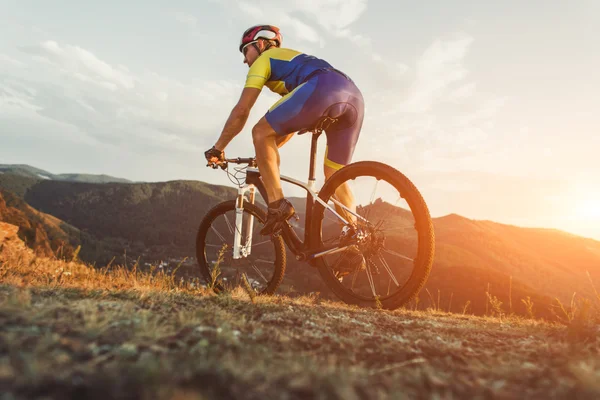 Low angle view of cyclist standing with mountain bike on trail a ...