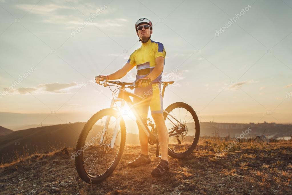Low angle view of cyclist standing with mountain bike on trail a ...