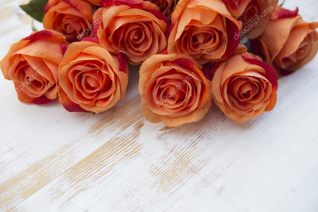 Orange roses on white rustic wooden background Stock Photo by ...