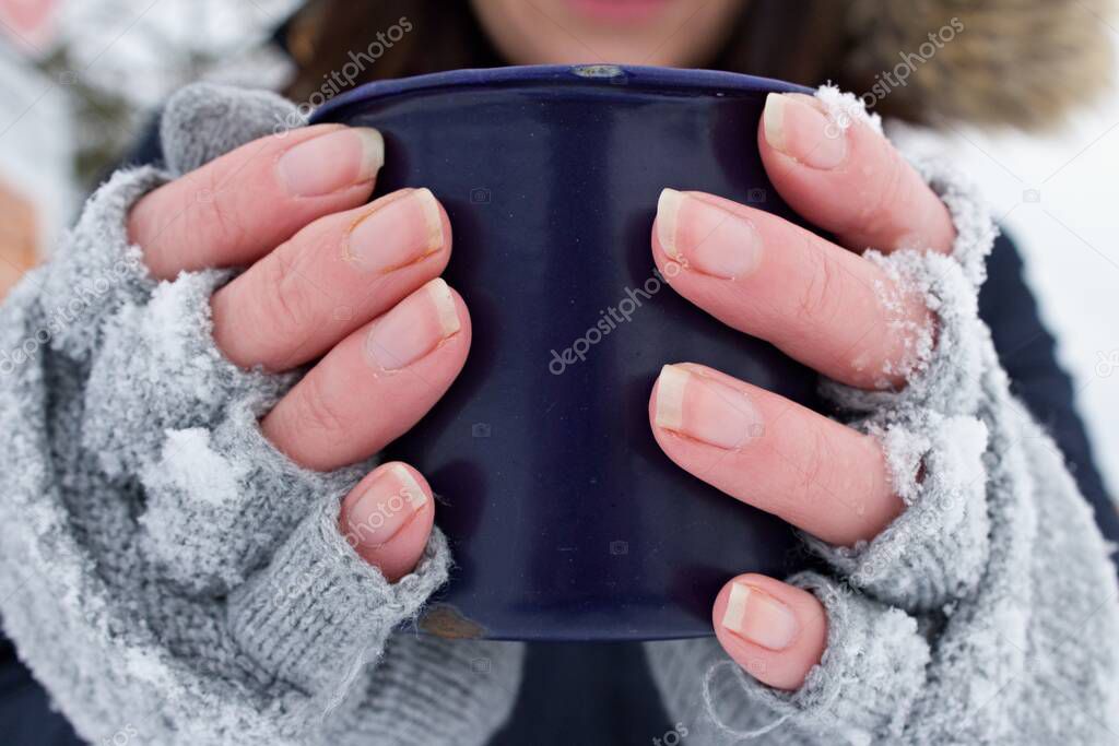 Mujer sosteniendo una taza en sus manos. Los guantes están cubiertos de ...