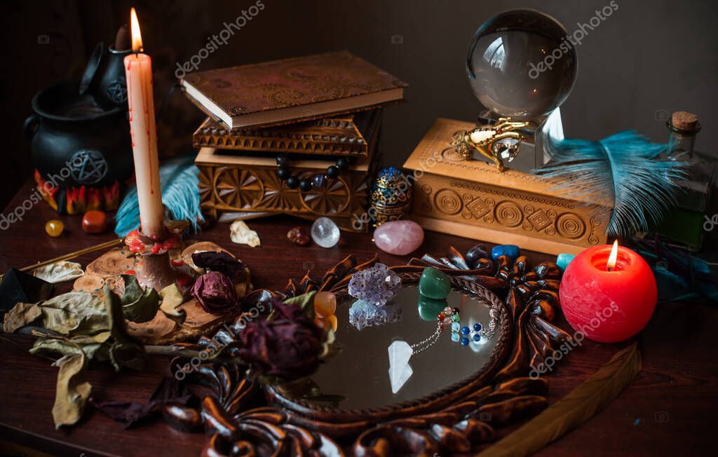 Una adivina, cosas de brujas en una mesa, velas y objetos adivinos. El ...