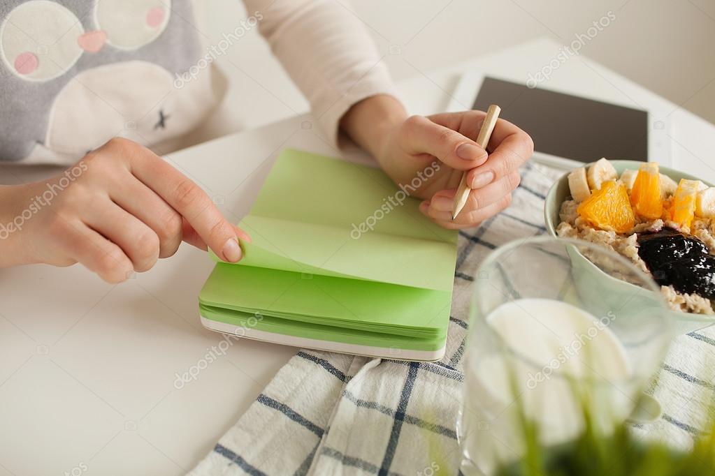 Woman making notes in notepad with healthy food on table — Stock Photo ...