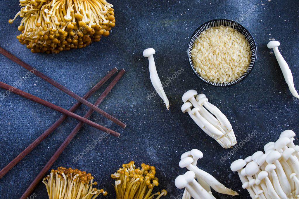 Hongos Enoki asiáticos de color marrón dorado y blanco, fondo vegetal ...