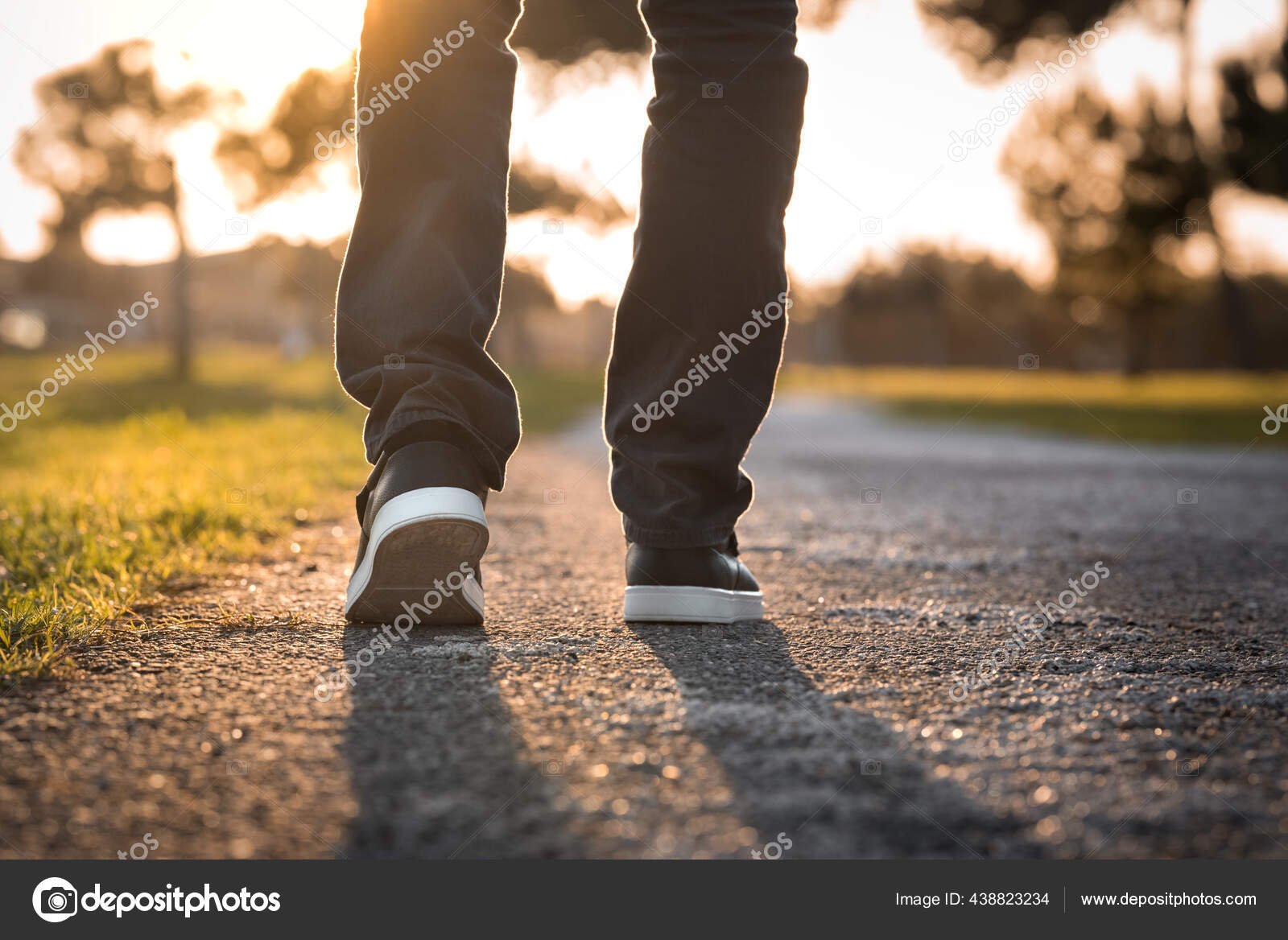 Man walking outdoors in the park at sunset. Closeup on shoe, taking a ...