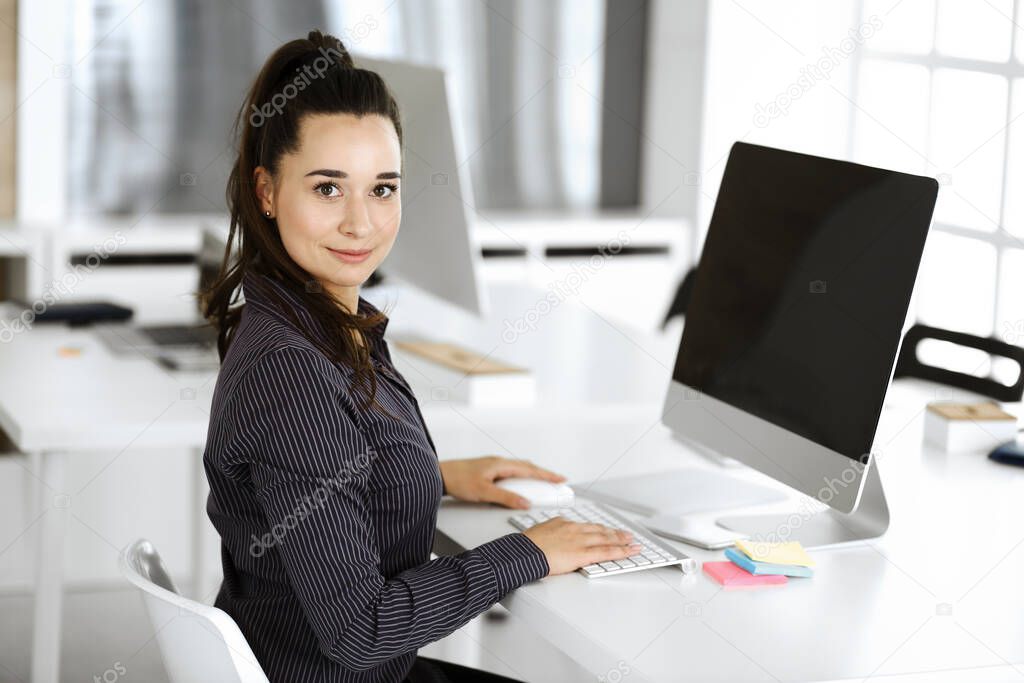 Mujer de negocios que utiliza la computadora en el lugar de trabajo en la oficina moderna ...