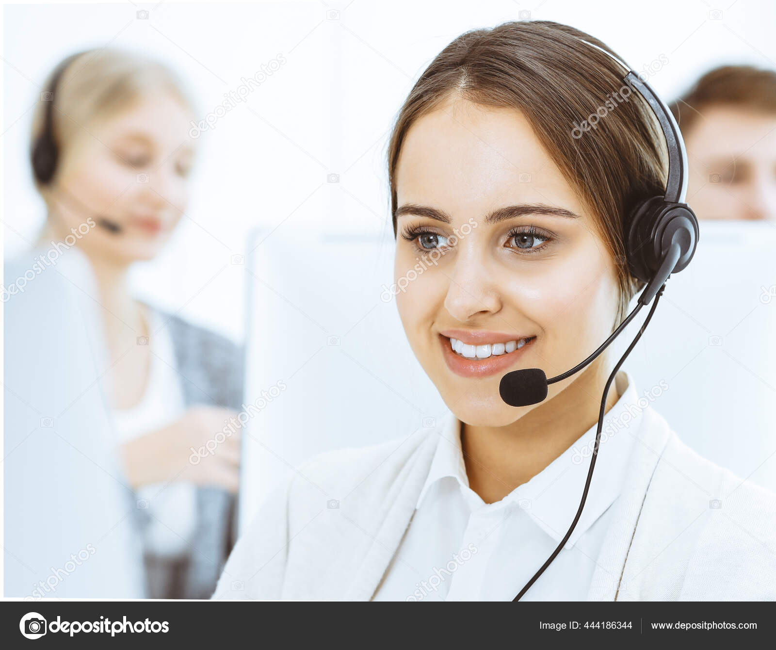 Call center. Group of diverse operators at work. Beautiful woman in headset communicating with ...