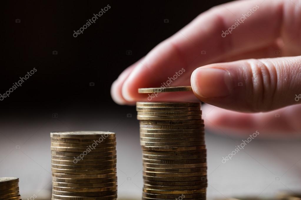 Hand putting coins to a stack on a wooden background Stock Photo by ...