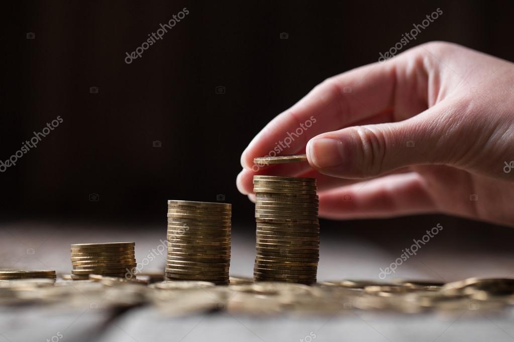 Hand putting coins to a stack on a wooden background Stock Photo by ...