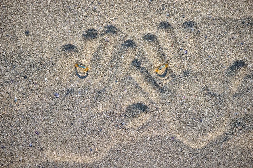 Two Hand shapes in the sand. Each hand has a golden wedding ring Stock ...
