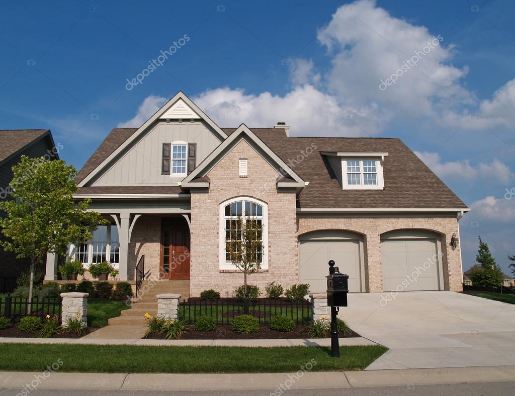 Small beige brick home with a two car garage in the front. — Stock ...