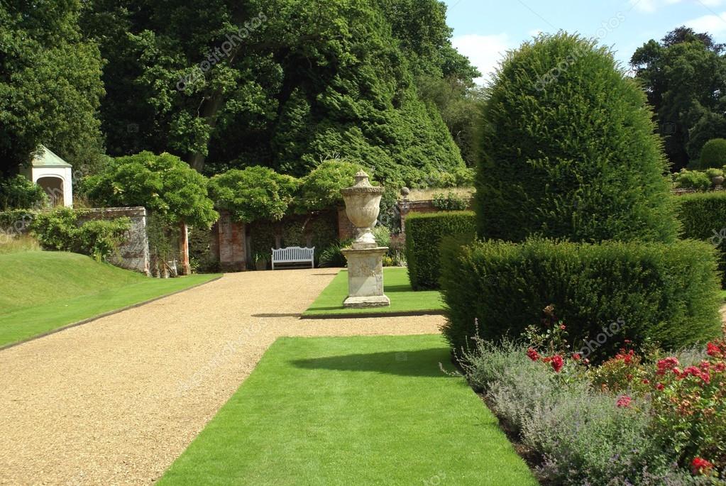 Garden pathway with an urn, bench, hedge, and a topiary tree — Stock ...