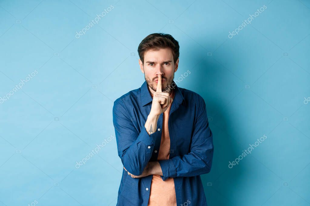 Hombre enojado callando, apretando el dedo a los labios y frunciendo el ...