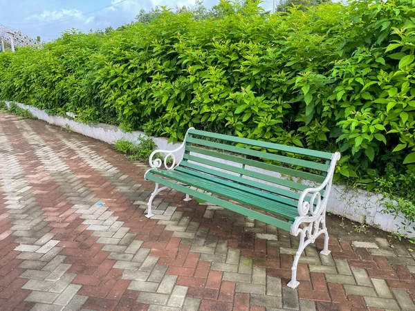 A beautiful bench painted green and white placed in a park with quite ...