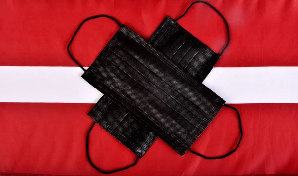 Black face protection mask on the Latvian flag. Covid - 19 epidemic and ...