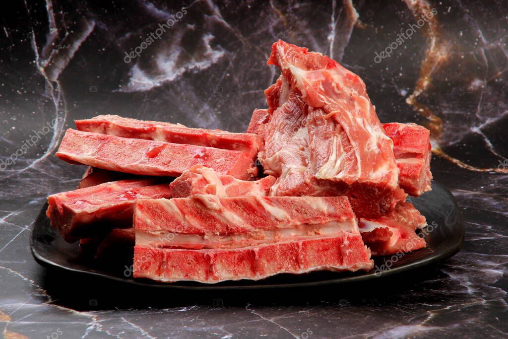 Carne cruda con hueso en plato de barro y fondo de mármol de lujo ...