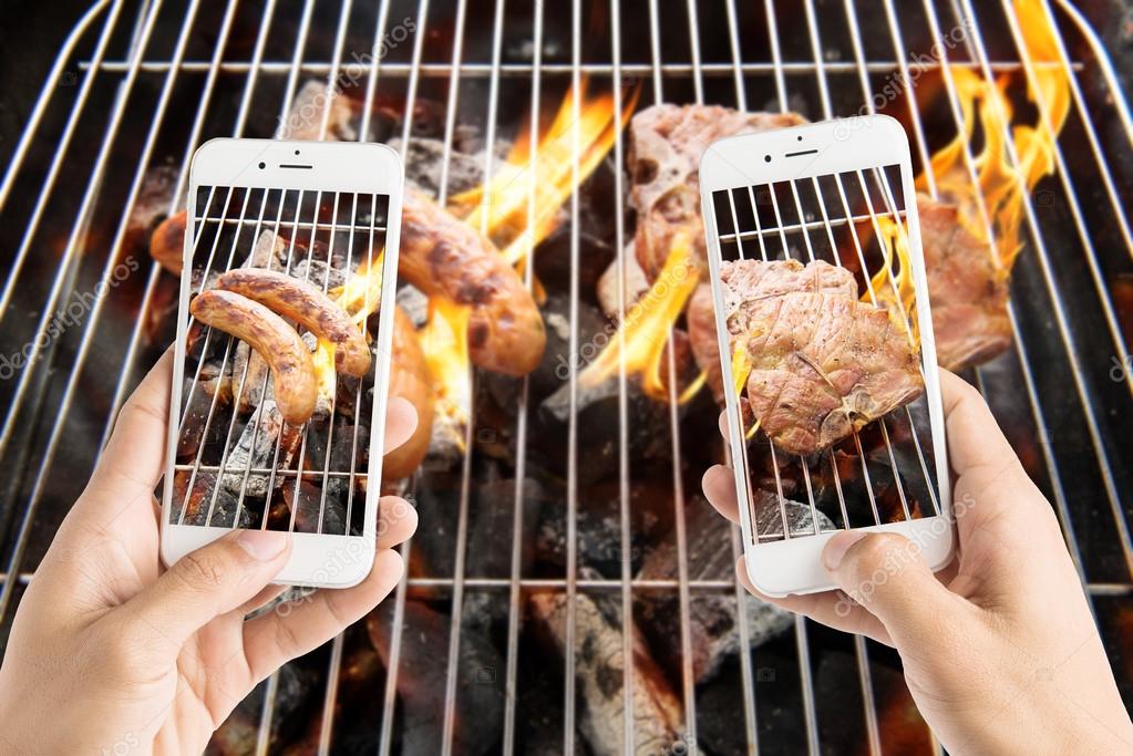 Friends using smartphones to take photos of sausage and pork cho ...