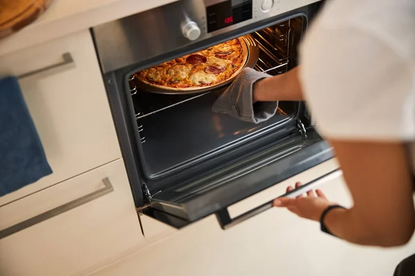 Using oven mitt while taking hot baking pan - Stock Image - Everypixel