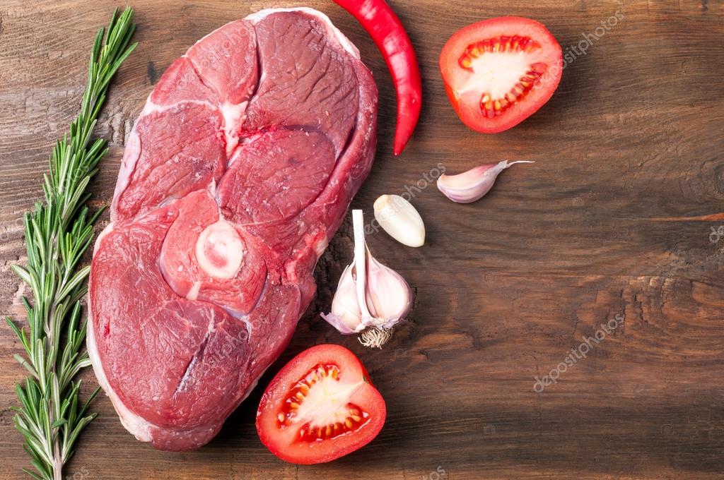 Raw meat mutton steak with rosemary, chili pepper, garlic and tomatoes ...