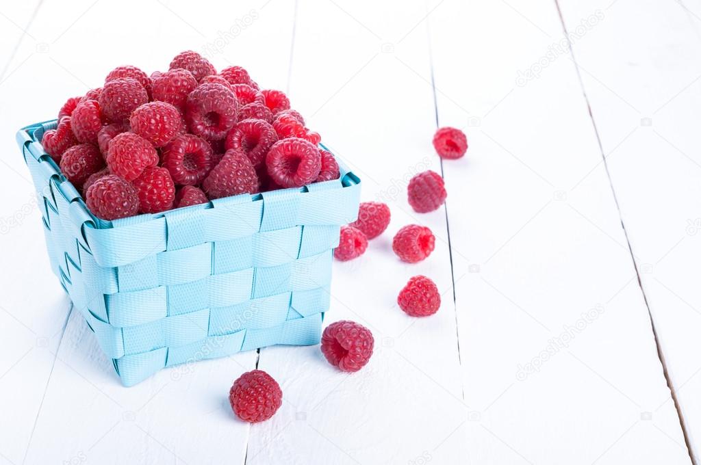 Frambuesas frescas en una canasta de mimbre sobre un fondo de madera ...