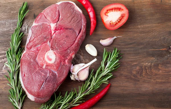 Raw meat mutton steak with rosemary, chili pepper, garlic and tomatoes ...