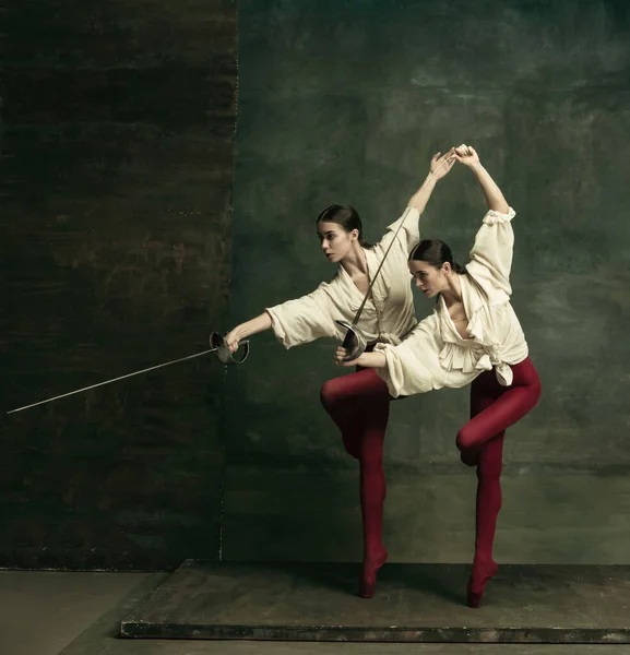Two young female ballet dancers like duelists with swords. Ballet and ...