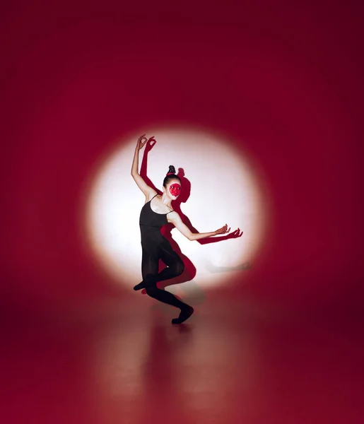Ballet dancers dancing over red studio background. Modern design ...