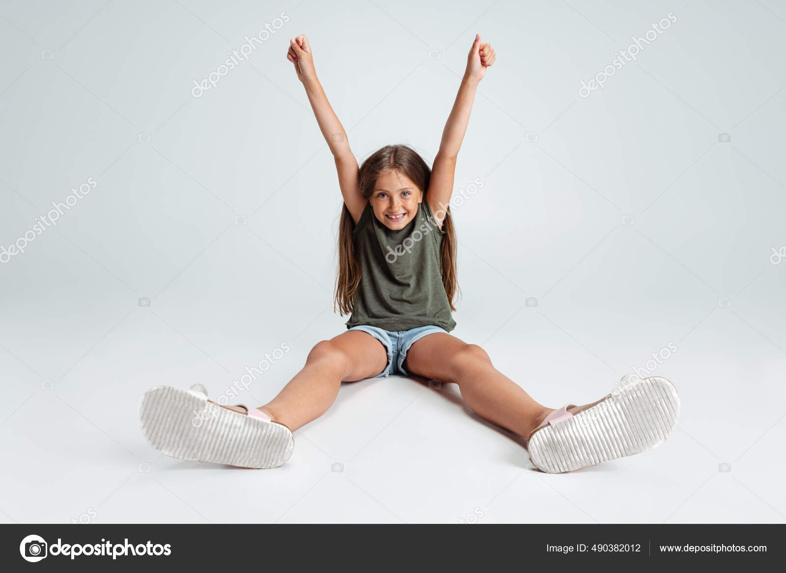 Portrait de belle petite fille mignonne, adolescent assis sur le sol isolé sur fond de studio ...