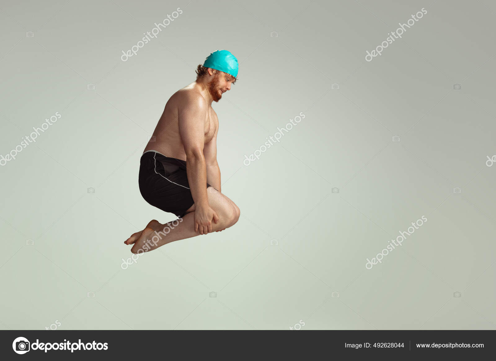 Funny dive. Cute red-headed man in red swimming shorts posing isolated ...