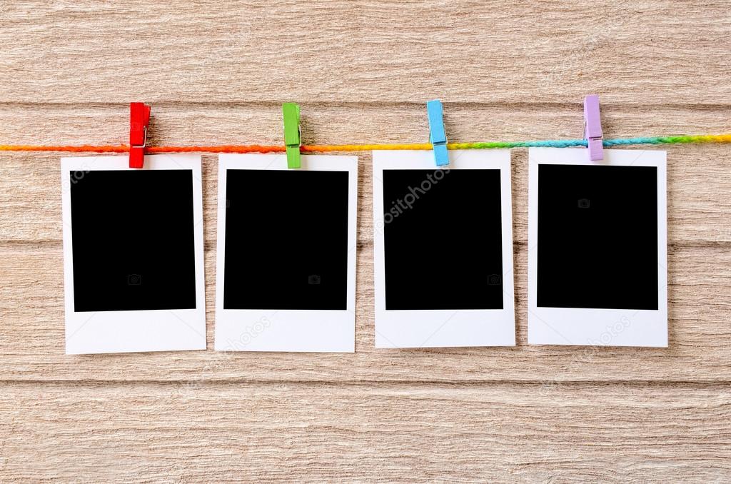 Empty black photo frames hanging with clothespins on wooden back ...